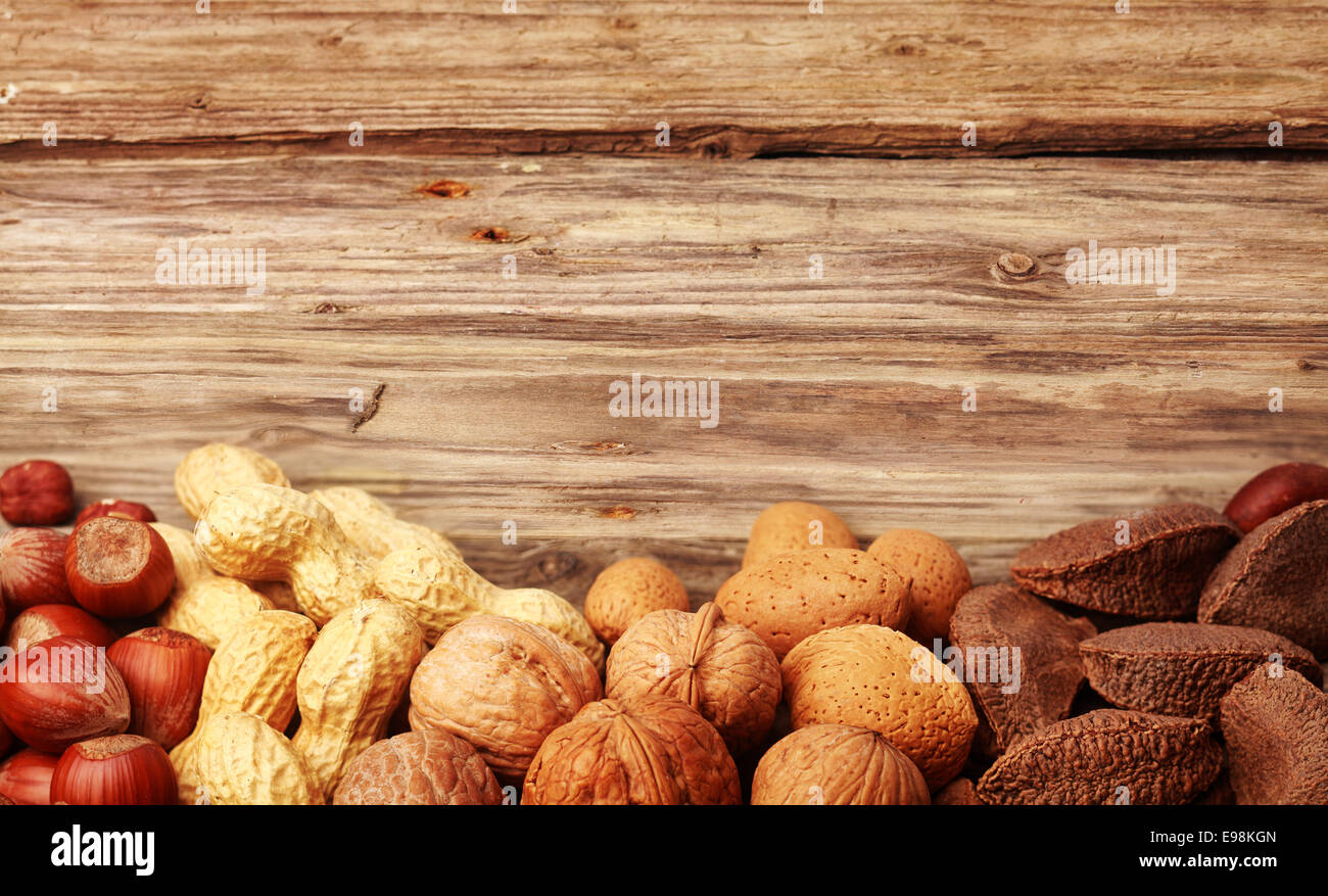 Border of assorted whole nuts in their shells including almonds ...