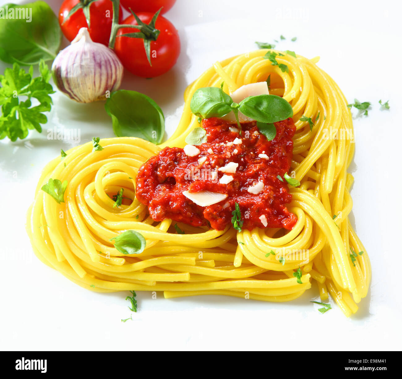 Cooked spaghetti arranged in a heart shape topped with tomato sauce and ...
