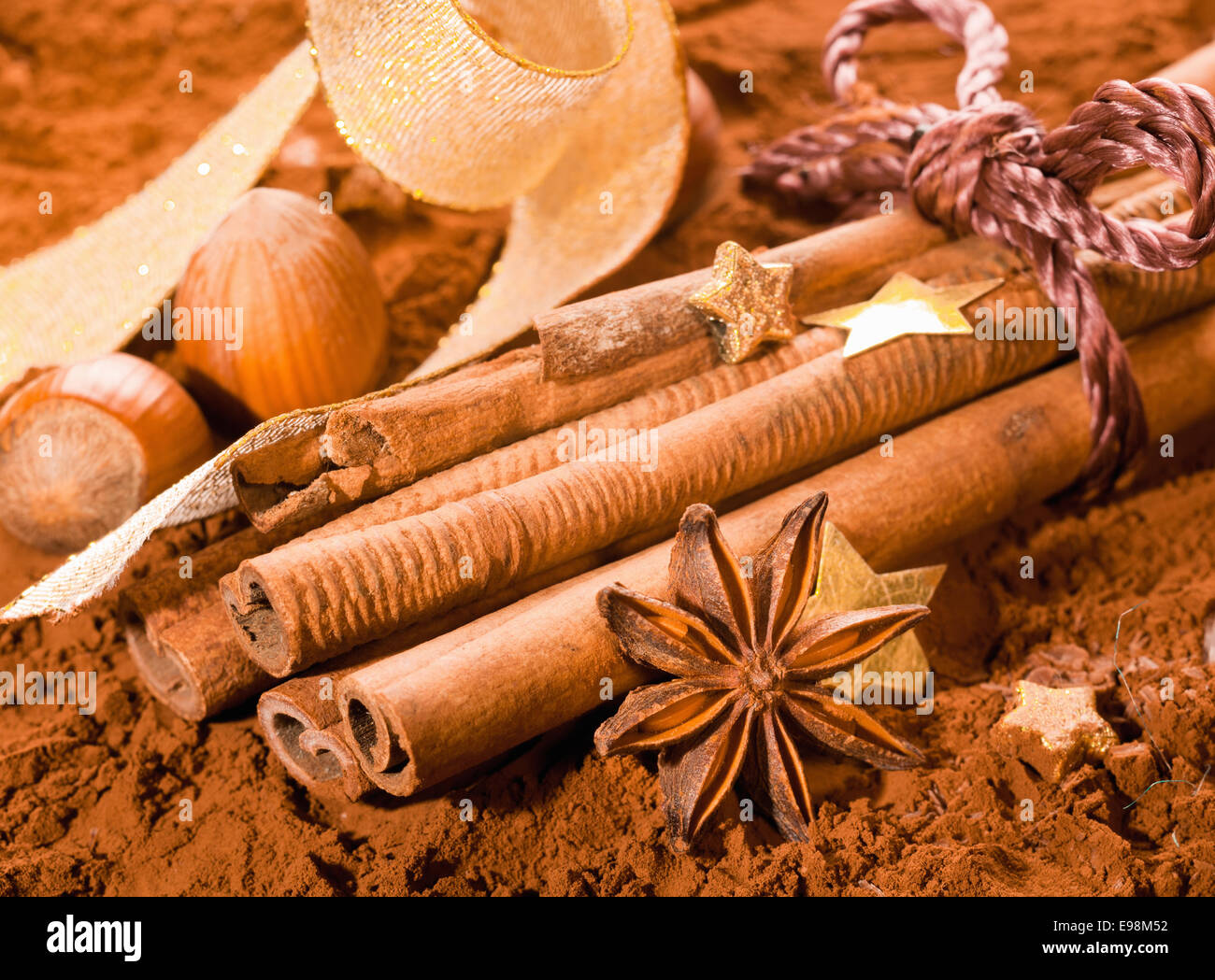 Bundle of Cinnamon with golden Stars, hazelnut and a bow on powdered ...