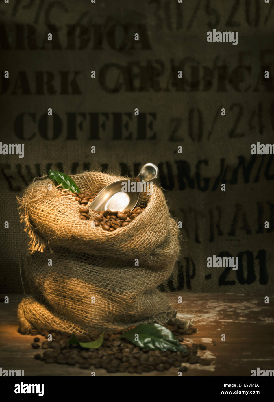 Small rustic hessian bag filled to overflowing with fresh roasted coffee beans and topped with a ...