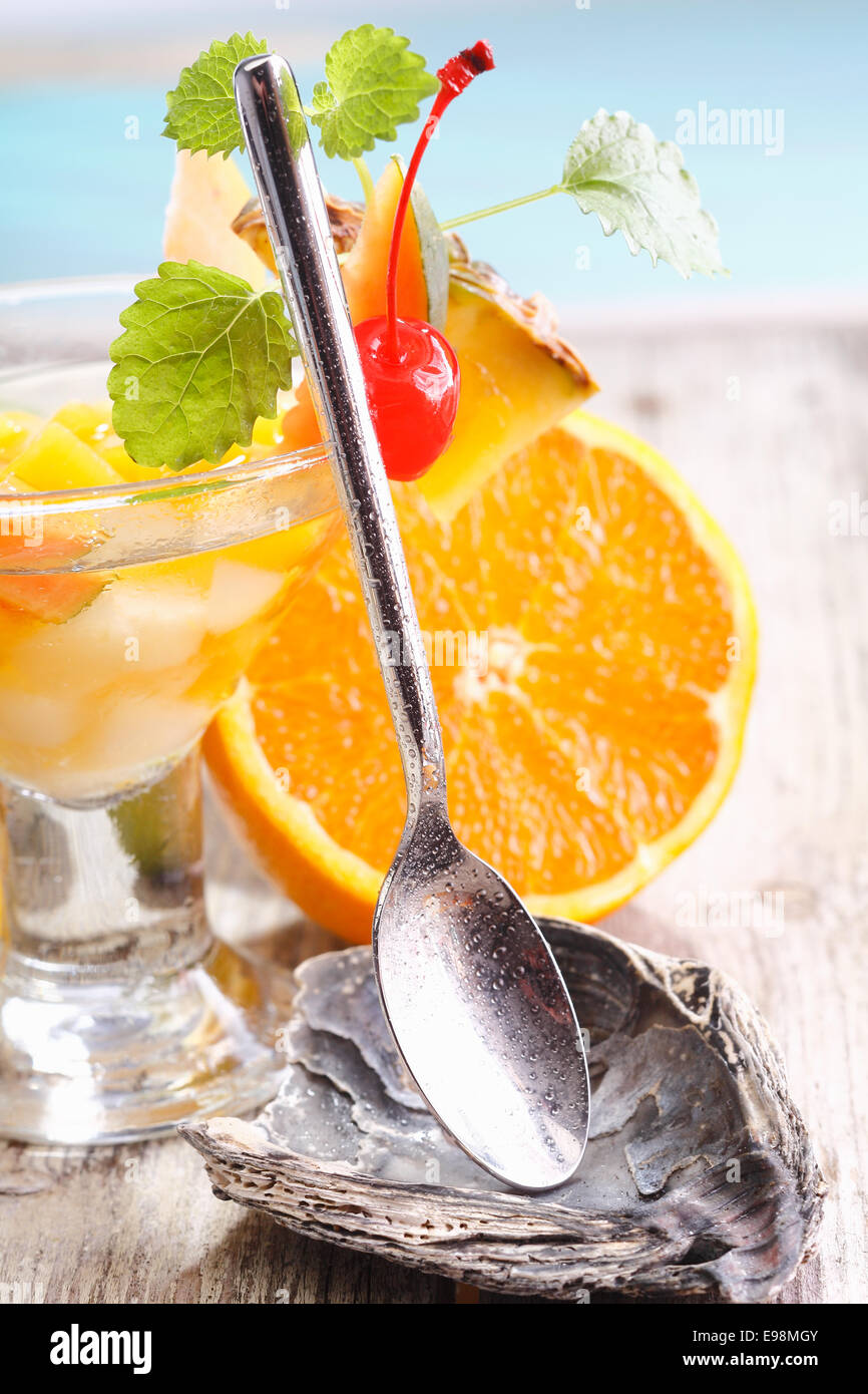 Serving spoon on a shell rest accompanying a glass of tropical fruit ...