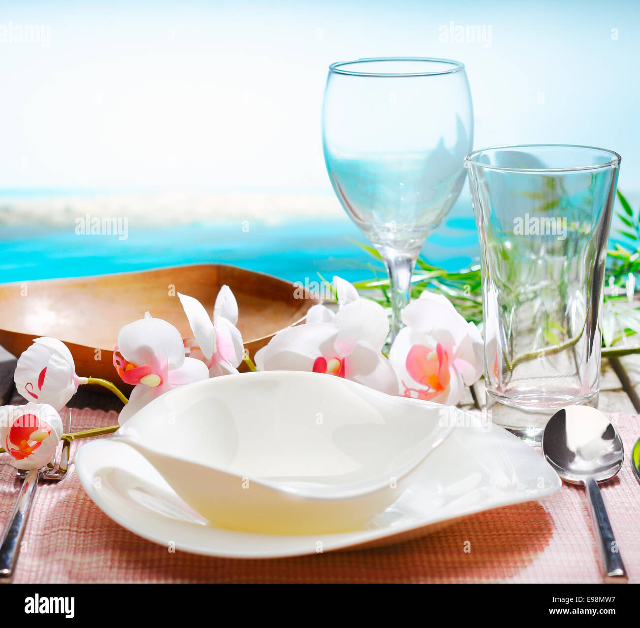 Stylish place setting with orchids and beautiful modern dinnerware in ...