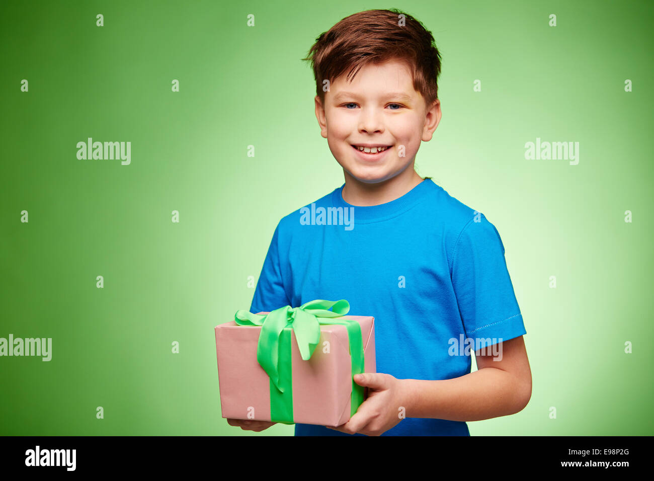 Cute boy with package looking at camera over green background Stock ...