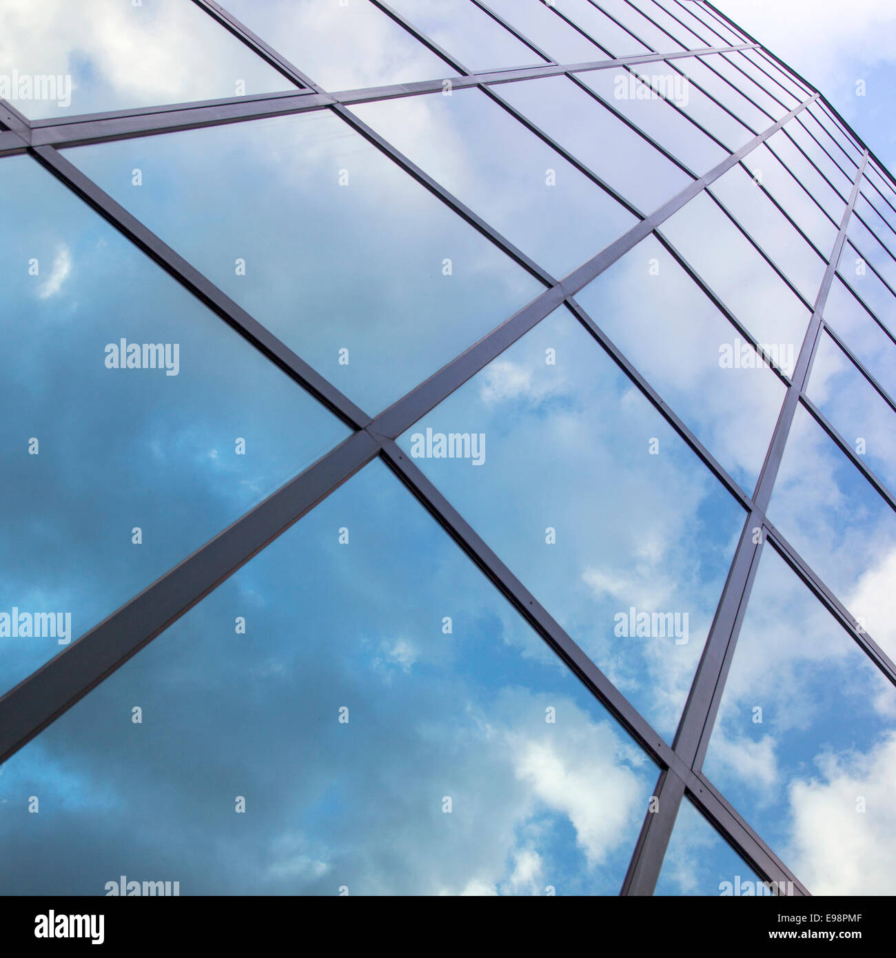 reflexions of clouds and blue sky in diagonal glass facade of modern ...