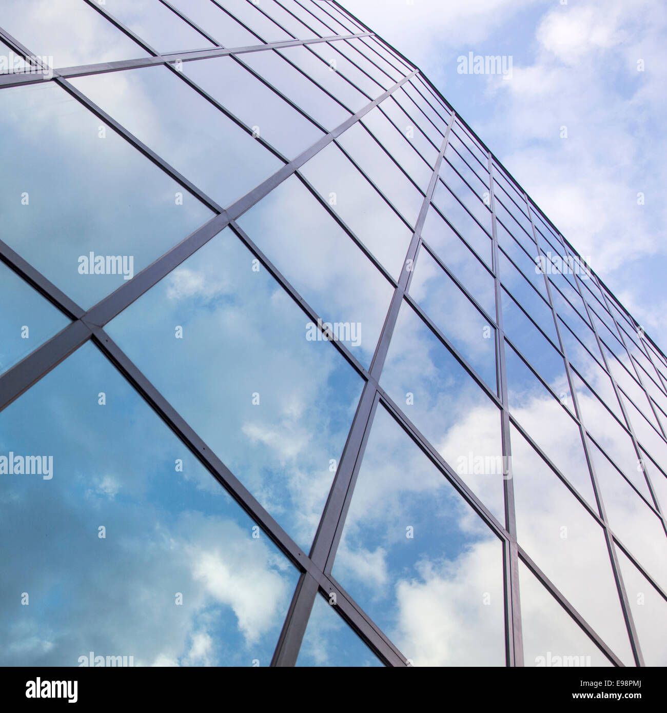 reflexions of clouds and blue sky in diagonal glass facade of modern ...