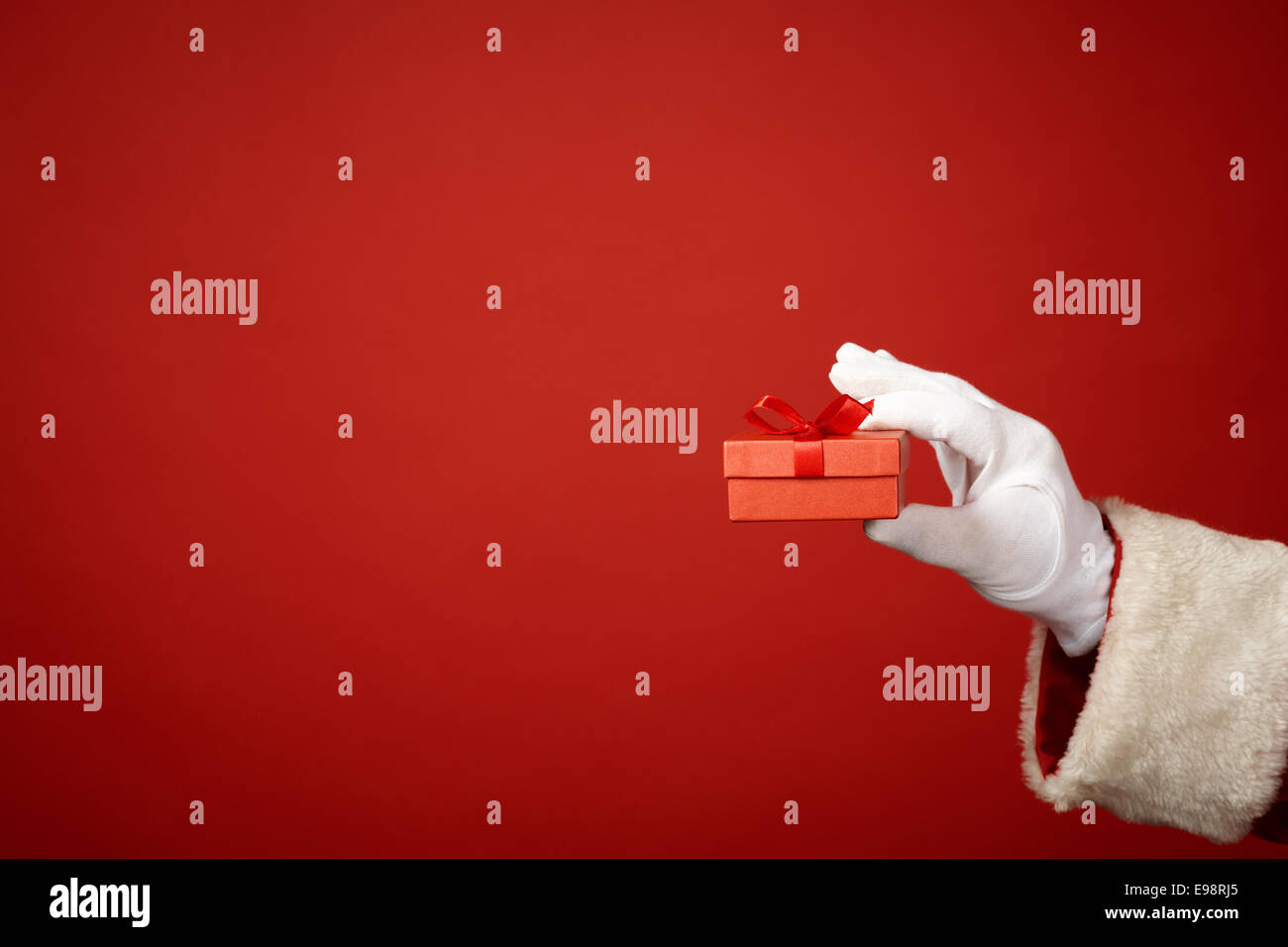Santa Claus hand in white glove showing small red package Stock Photo ...