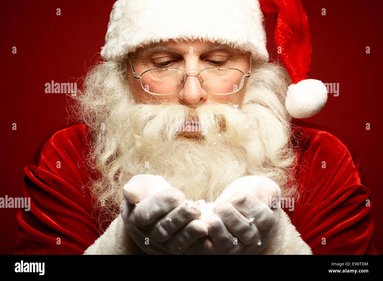 Santa Claus in eyeglasses blowing snow from his palms Stock Photo - Alamy