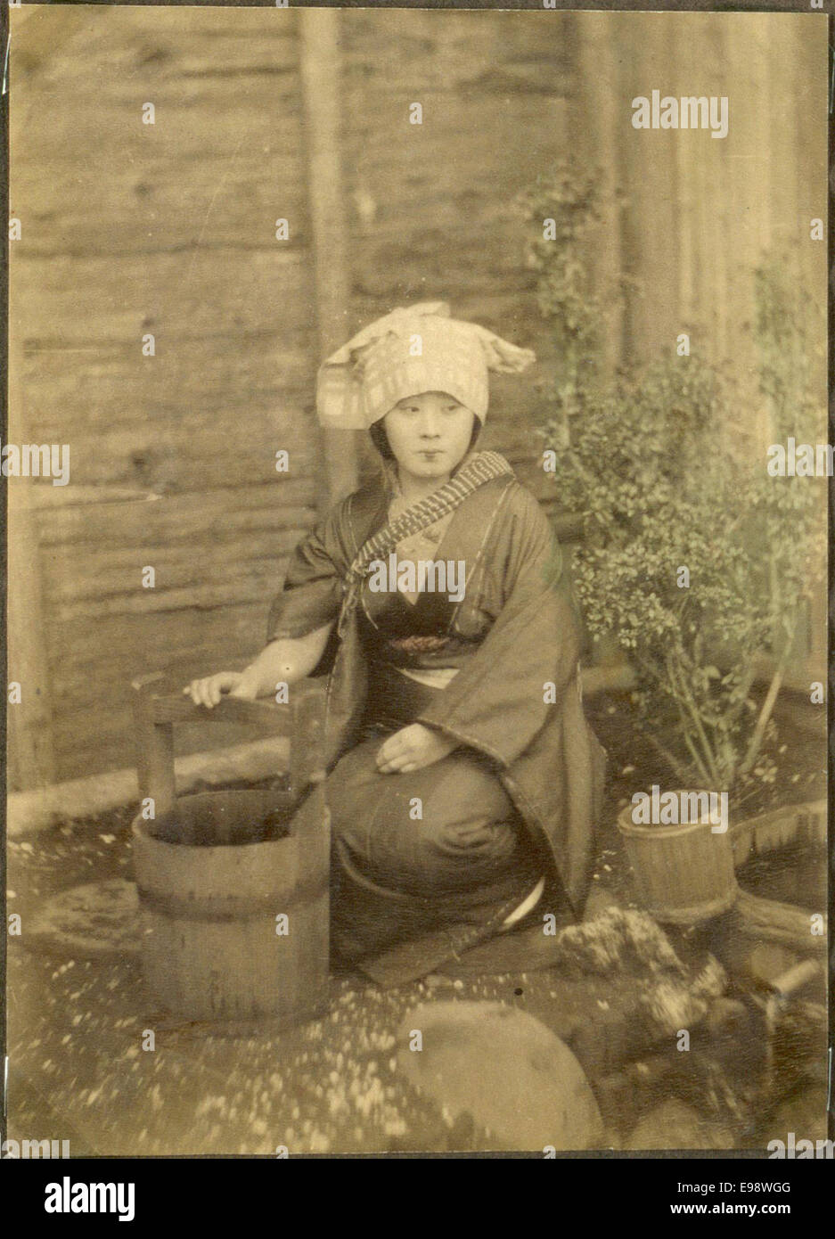 This photograph captures a woman in Japan carrying a water bucket ...