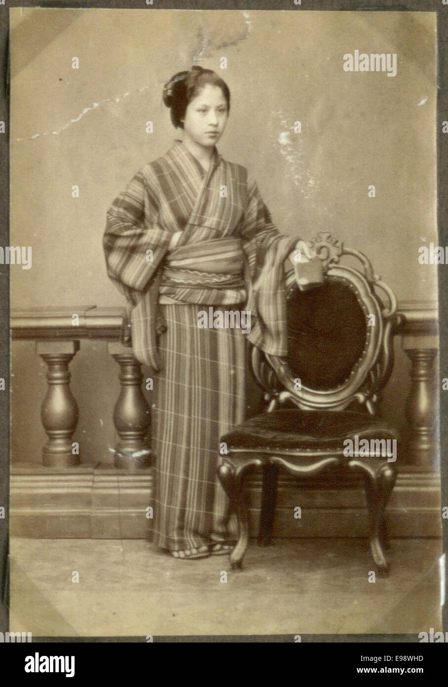 A vintage photograph of a woman seated in a traditional Japanese chair ...