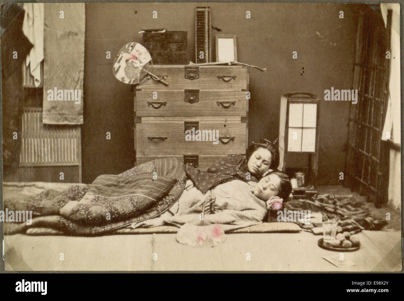 This photograph shows two women sleeping on a traditional Japanese ...