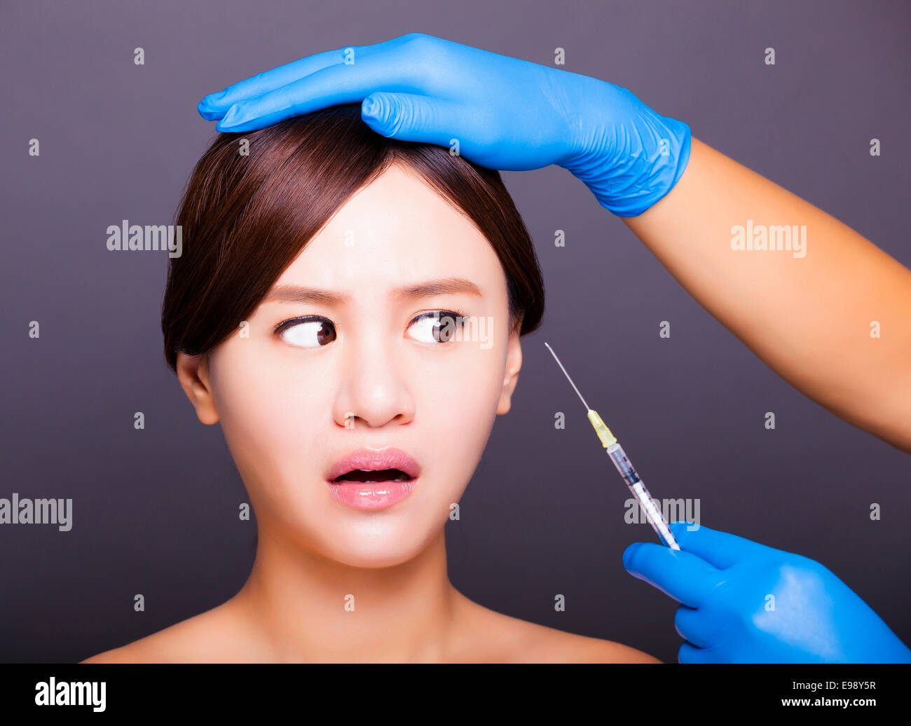 surprised young woman looking at needle for injection into face Stock ...