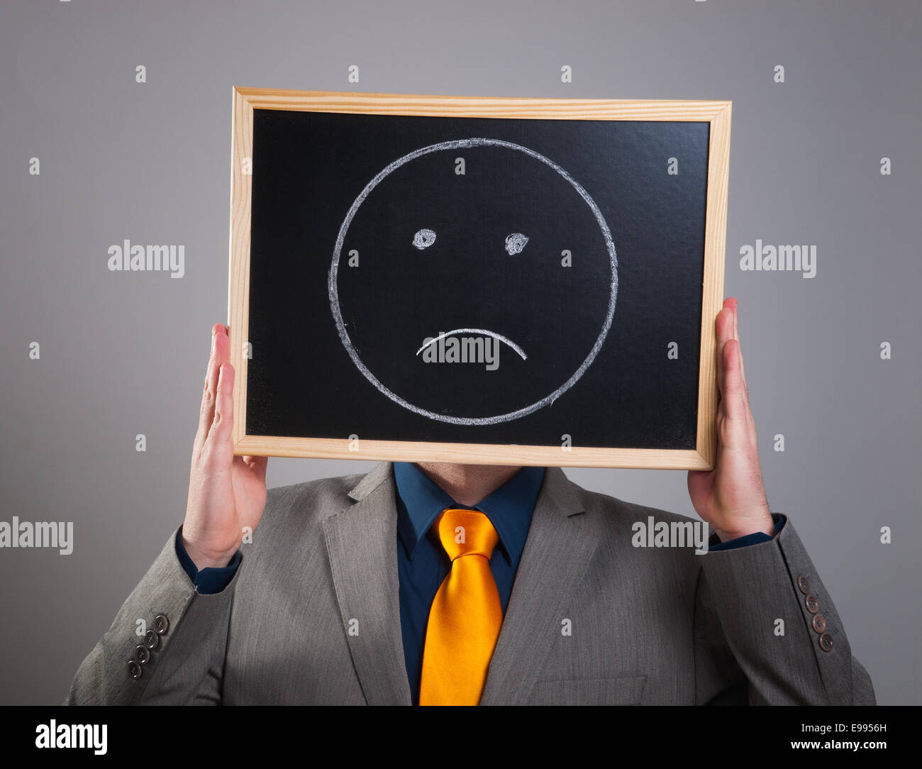 Businessman hiding his face with a white billboard with a sad face on ...