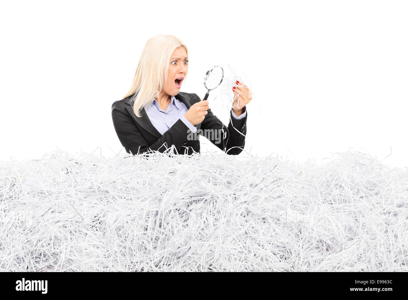 Shocked woman looking at a pile of shredded paper through a magnifier ...
