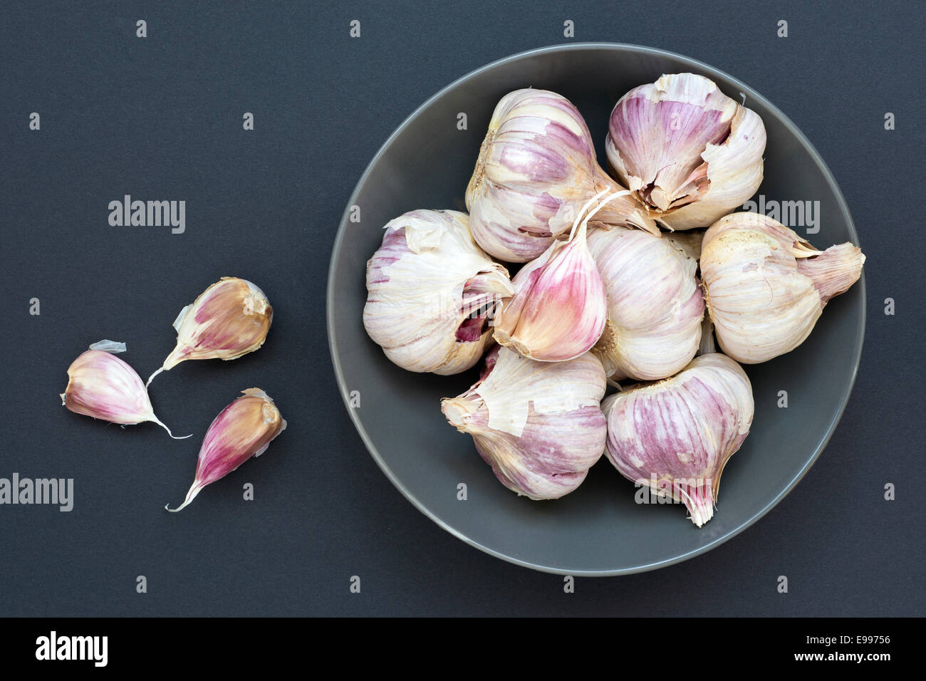 gray bowl full of garlic on dark gray background Stock Photo - Alamy