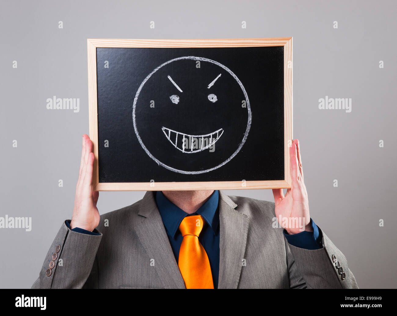 Businessman hiding his face with a white billboard with a evil face on ...