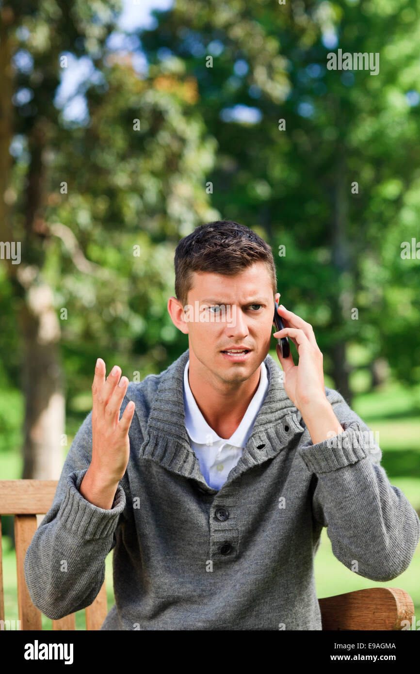Young man phoning on the bench Stock Photo - Alamy