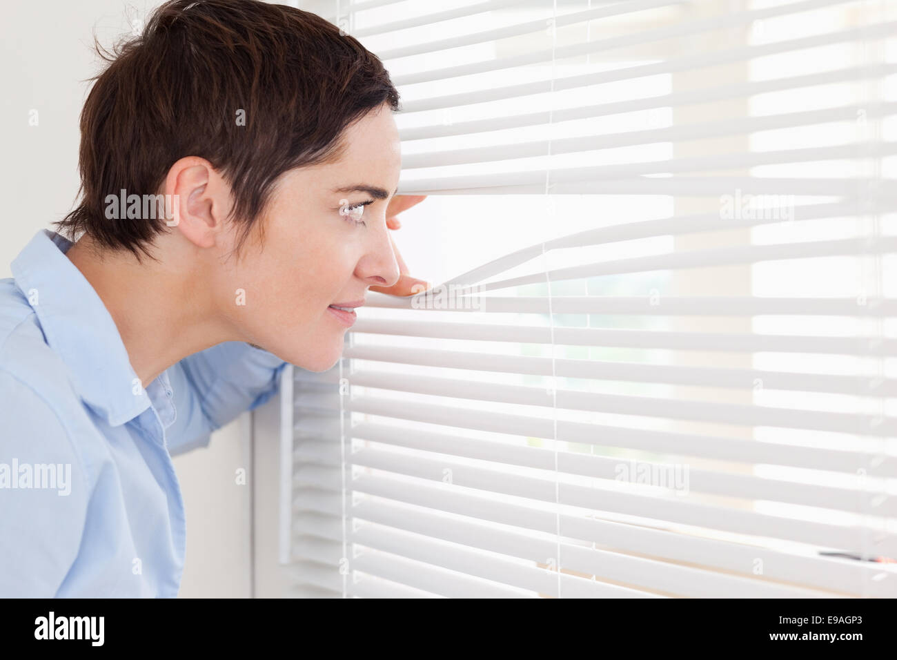 Beautiful woman peeking out a window Stock Photo - Alamy