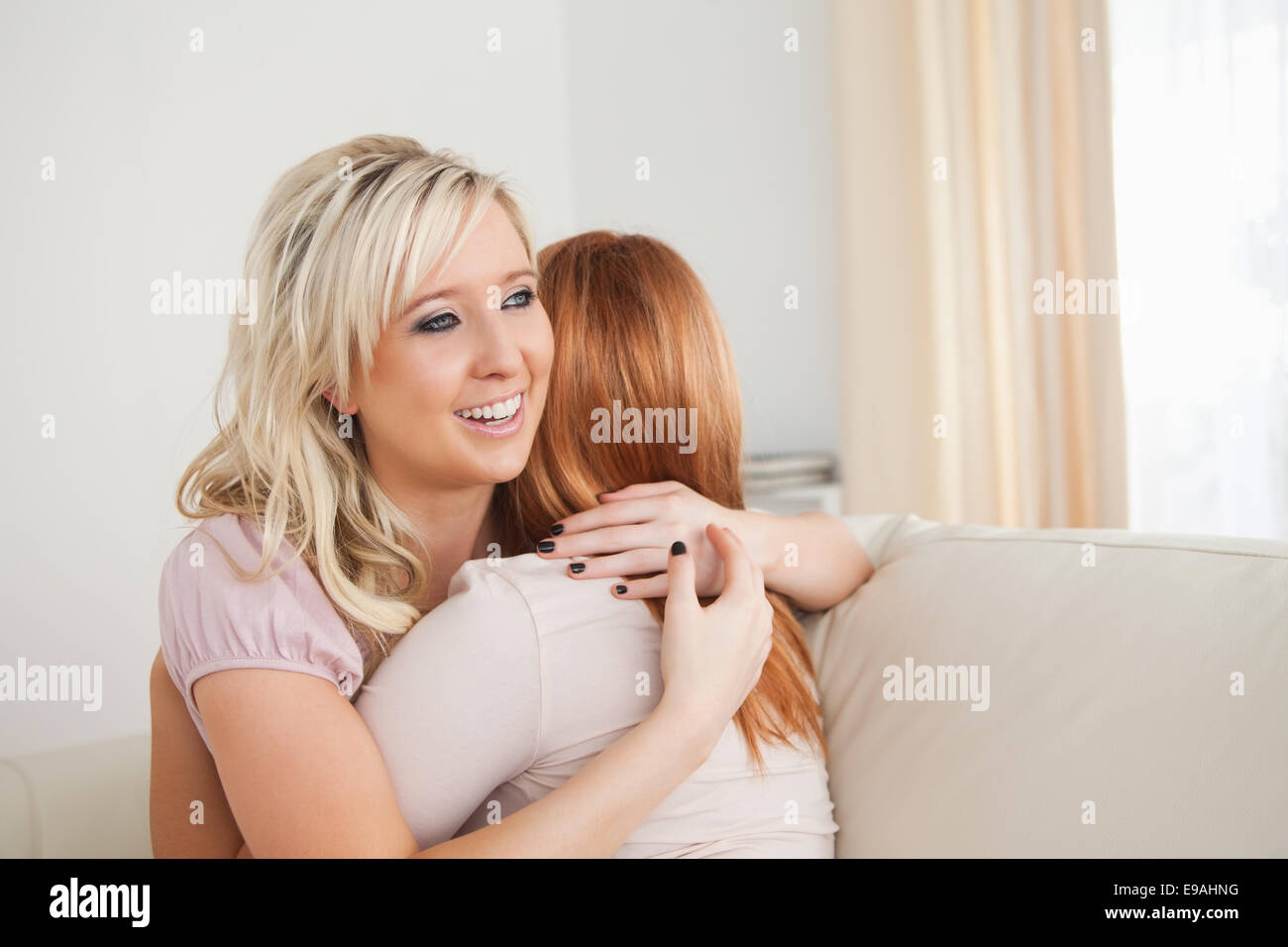 Hugging Friends sitting on a sofa Stock Photo - Alamy
