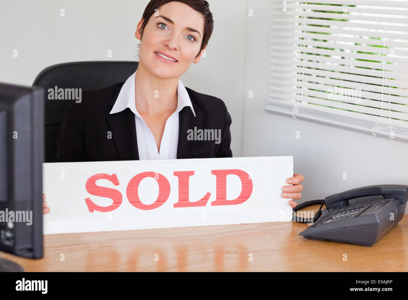 Smiling real estate agent with a sold panel Stock Photo - Alamy