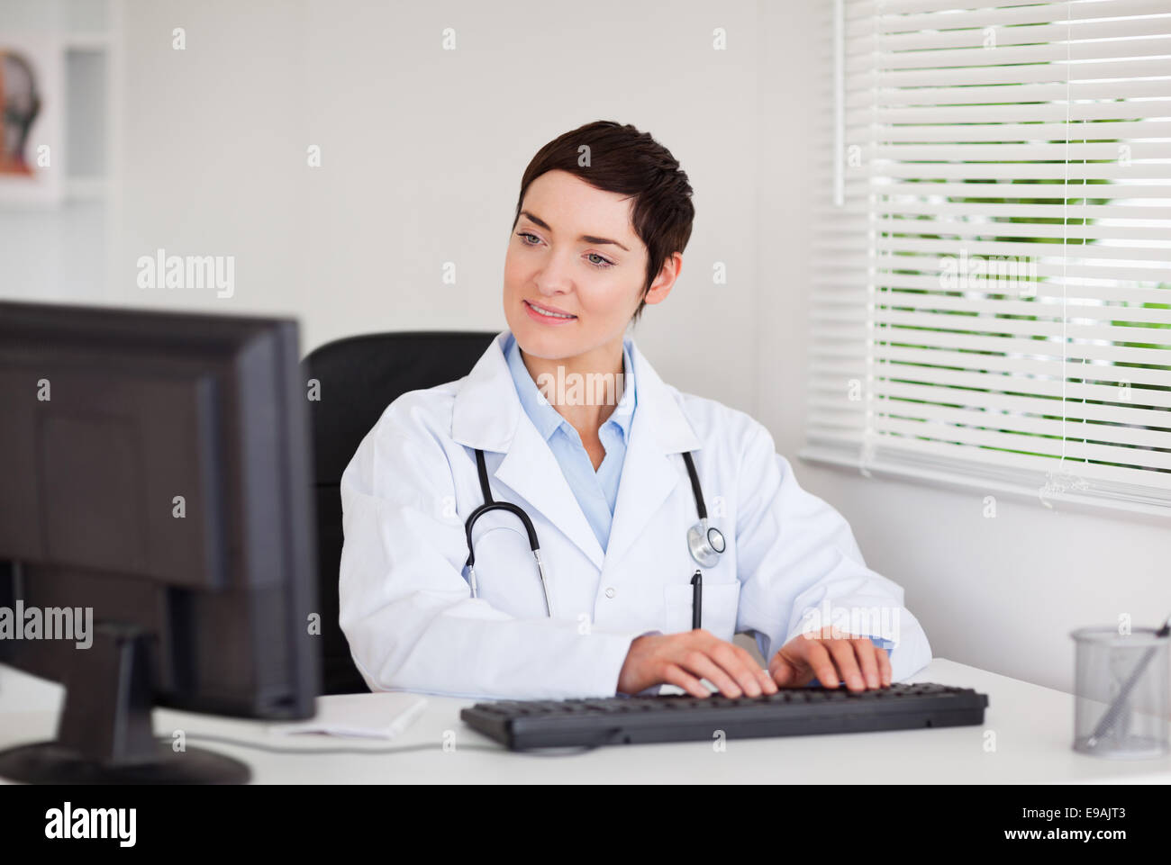 Charming doctor typing with her computer Stock Photo - Alamy