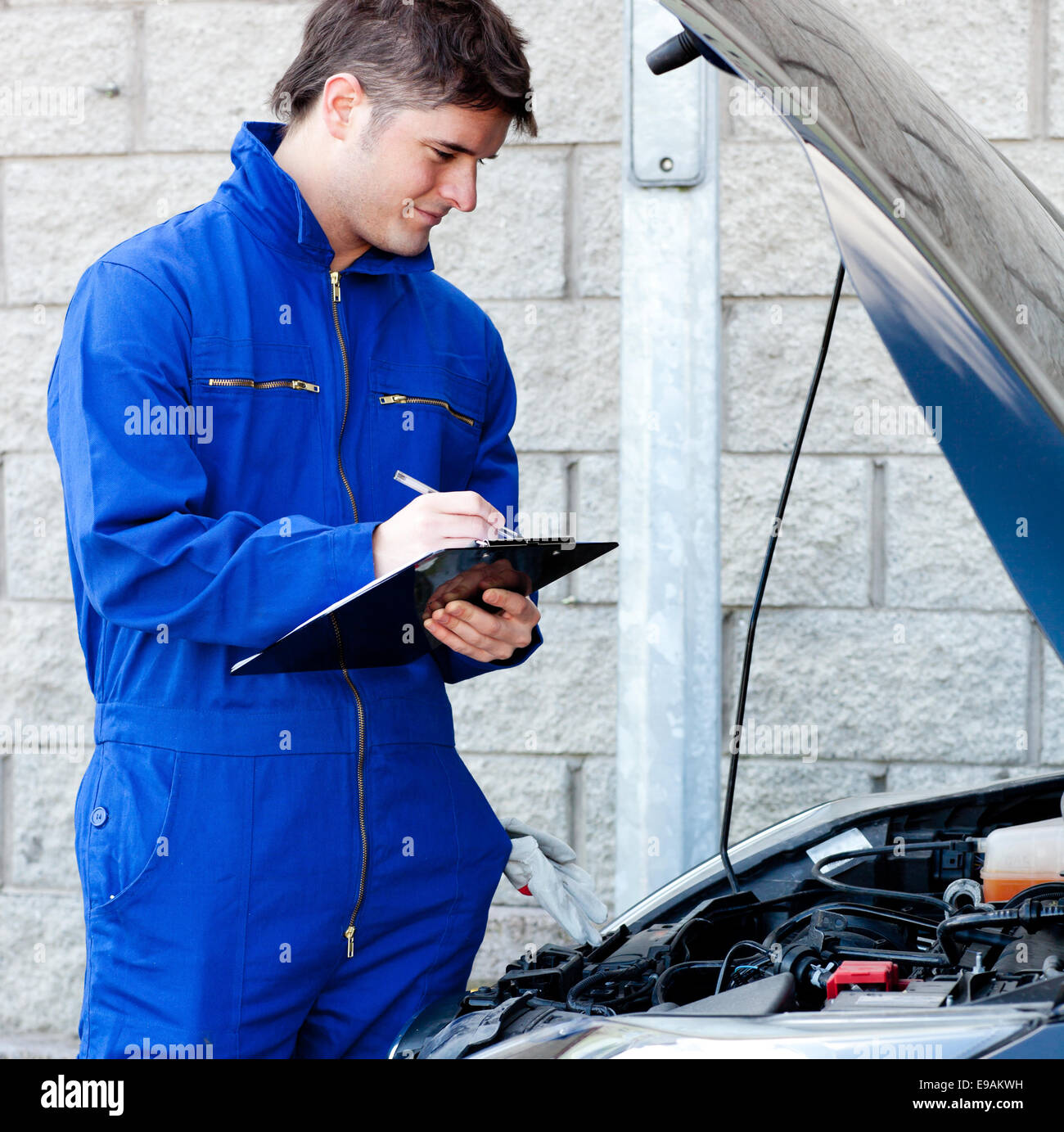 Handsome mechanic writing on a clipboard Stock Photo - Alamy