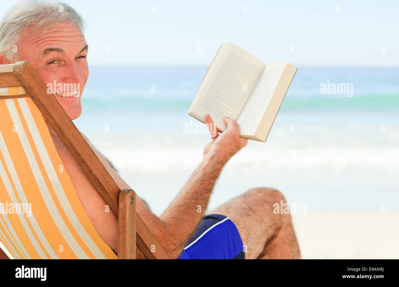 Senior man reading a book at the beach Stock Photo - Alamy