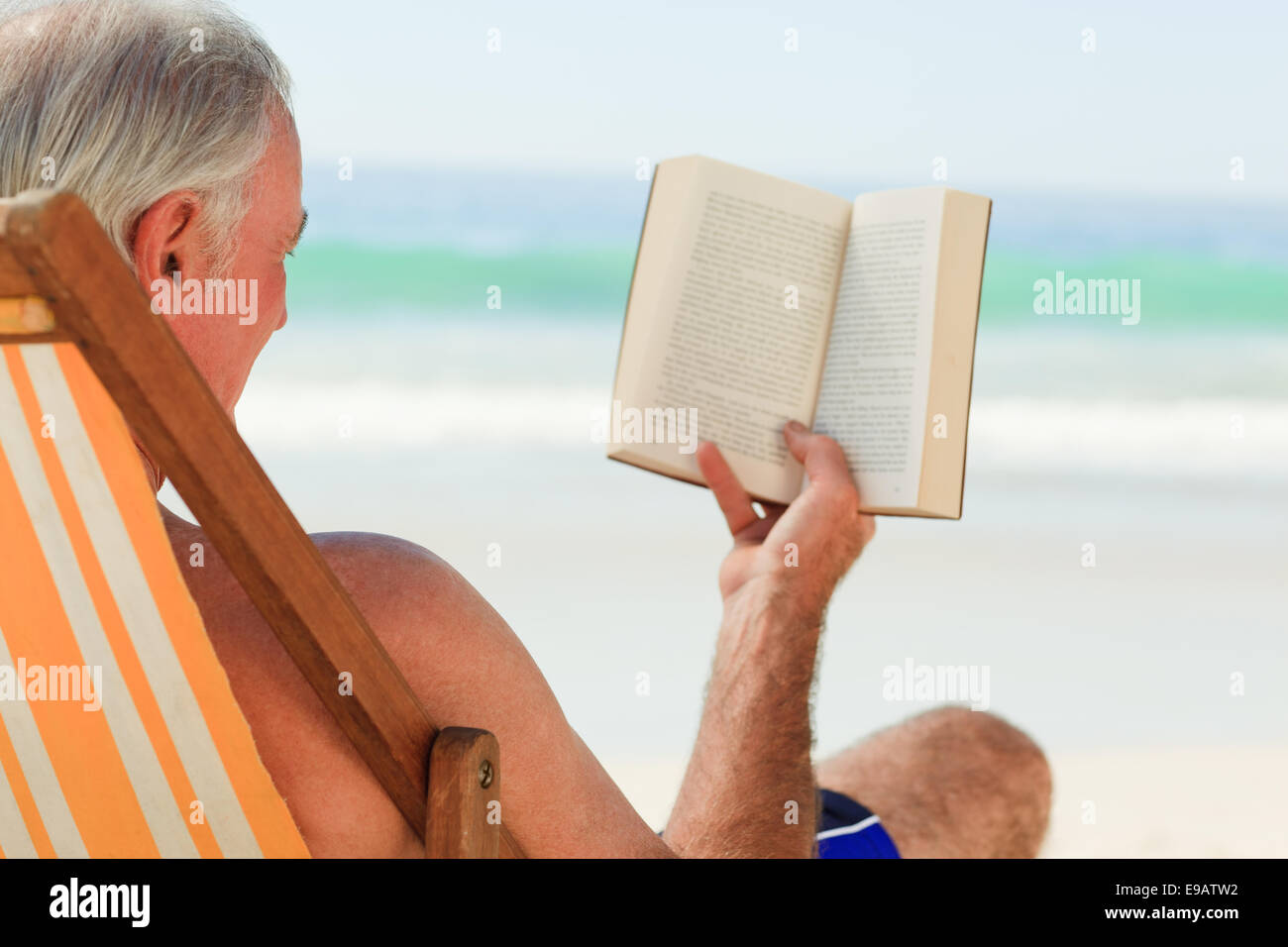 Senior man reading a book at the beach Stock Photo - Alamy