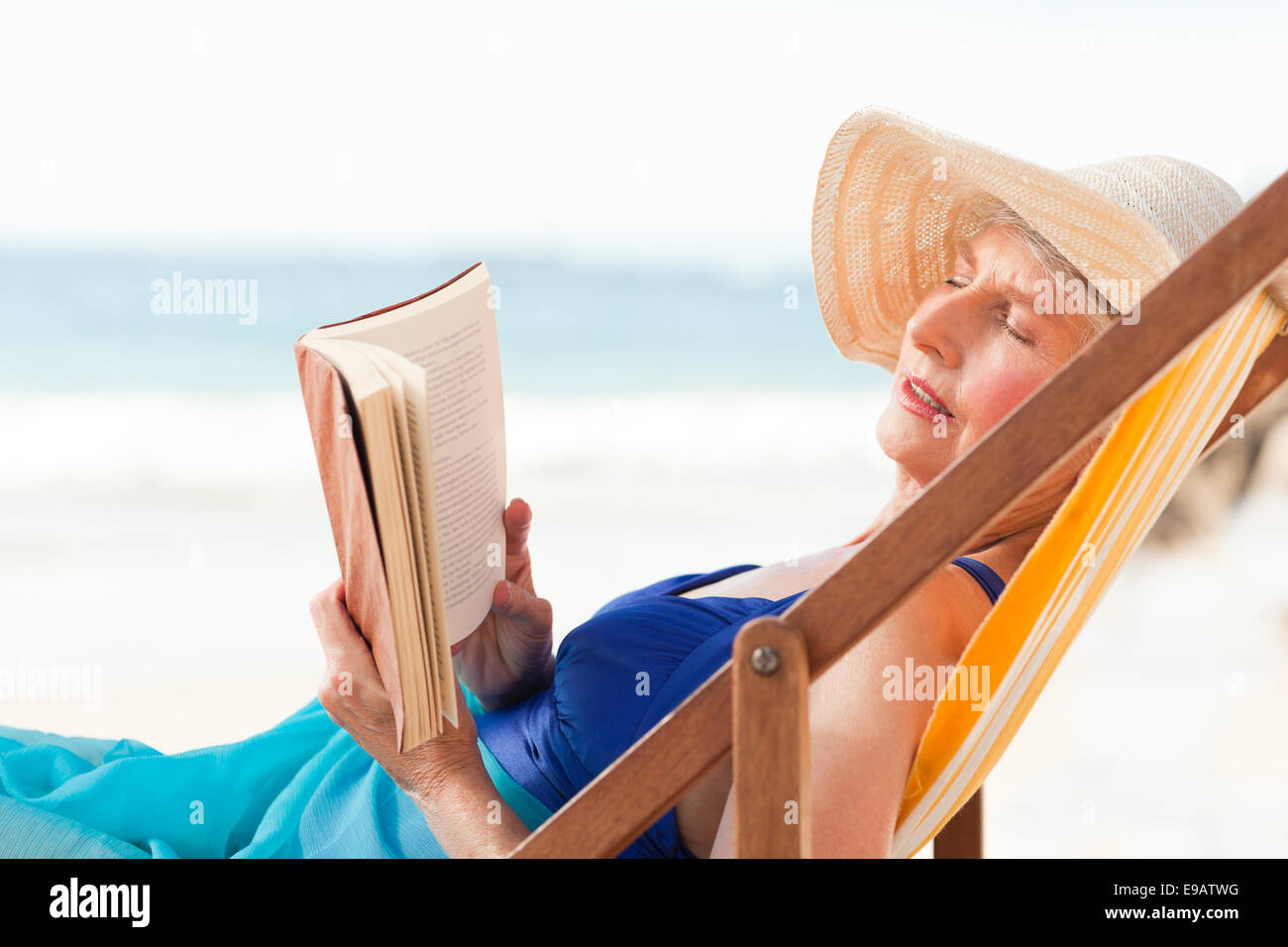 Elderly woman reading a book at the beach Stock Photo - Alamy