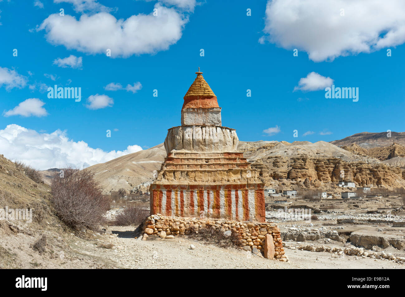 Colourfully decorated Buddhist stupa on a track in a vast landscape ...