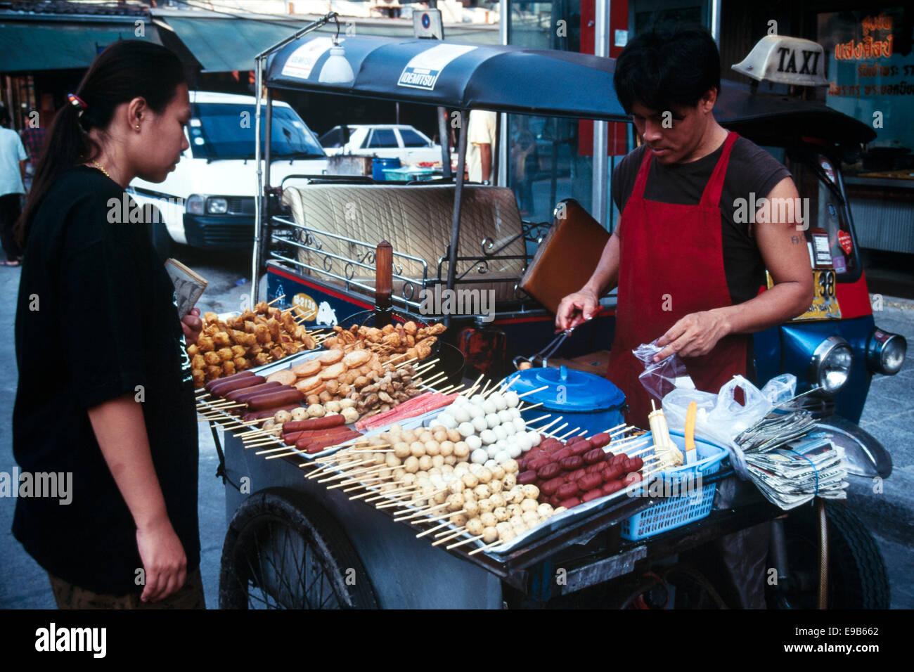 local female buying fast food from a street stall vendor in bangkok ...