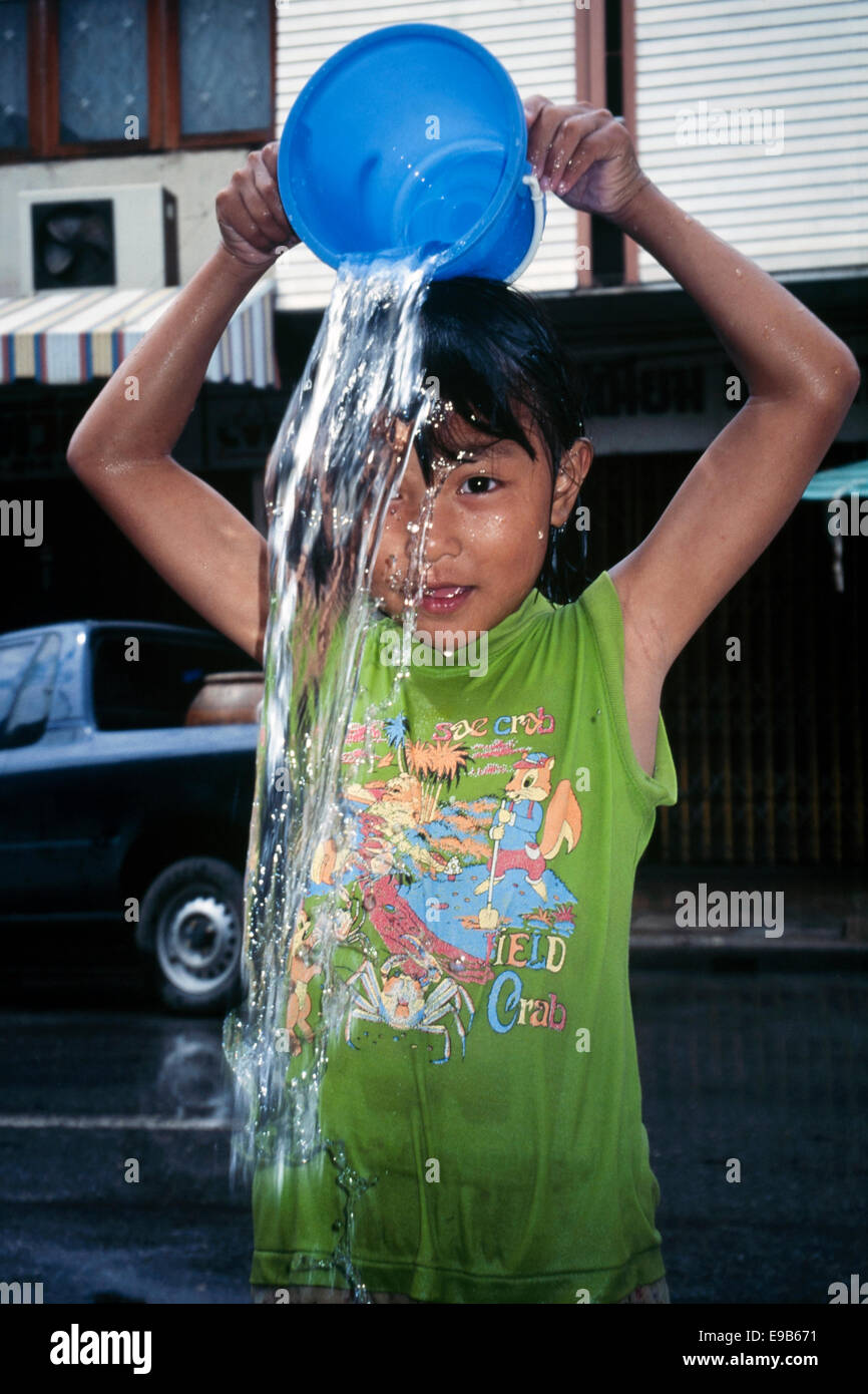 young girl tips a pail of water over herself to cool down in a bangkok ...