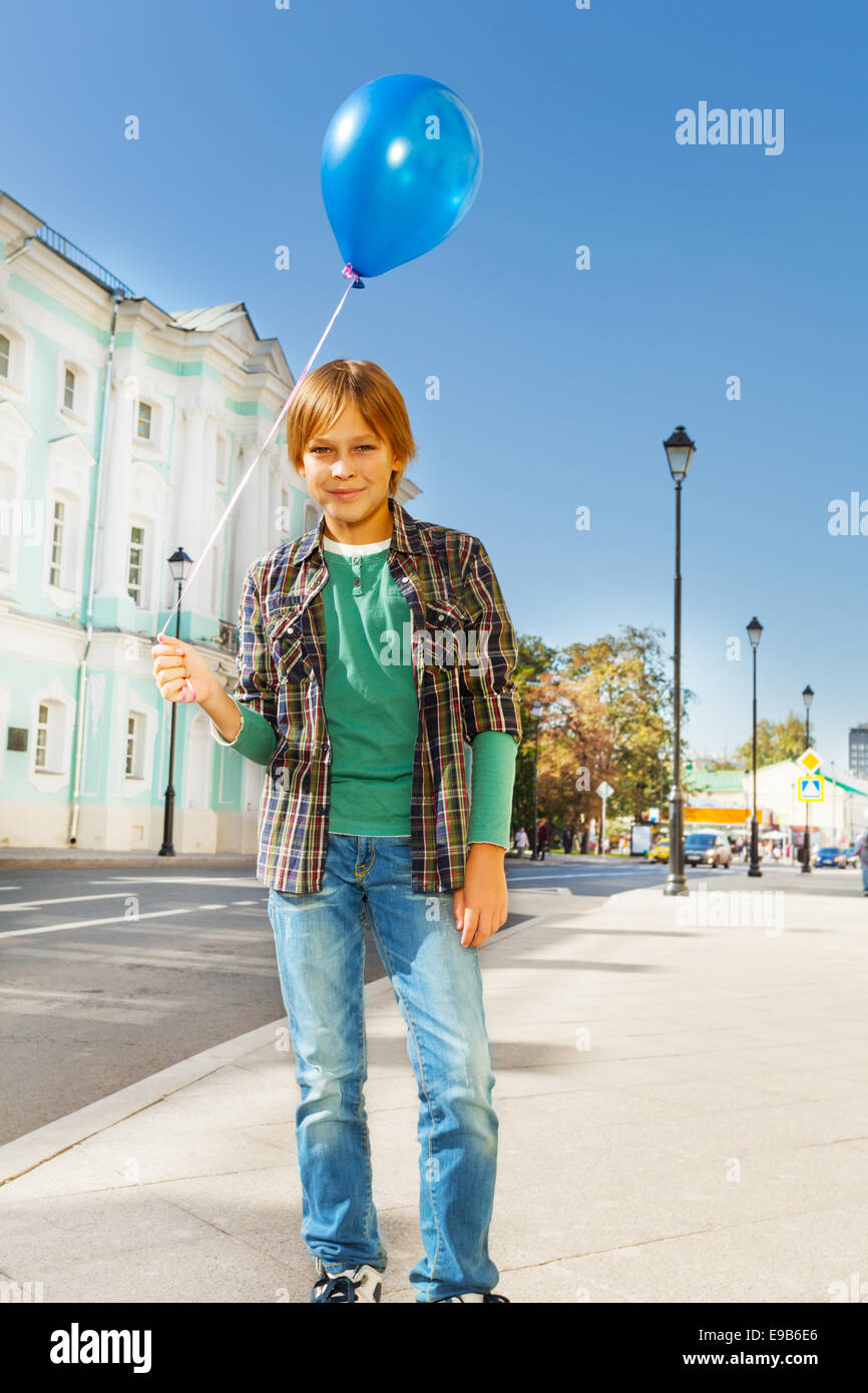Boy with blue flying balloon standing on street Stock Photo - Alamy
