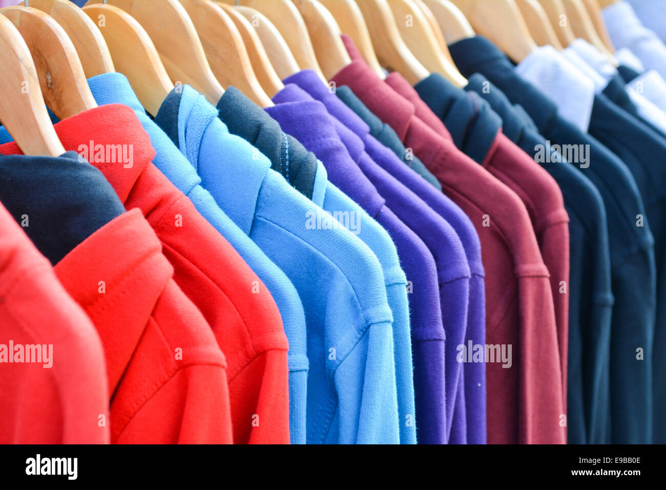 Hooded tops hanging up in groups of three one behind the other in a ...