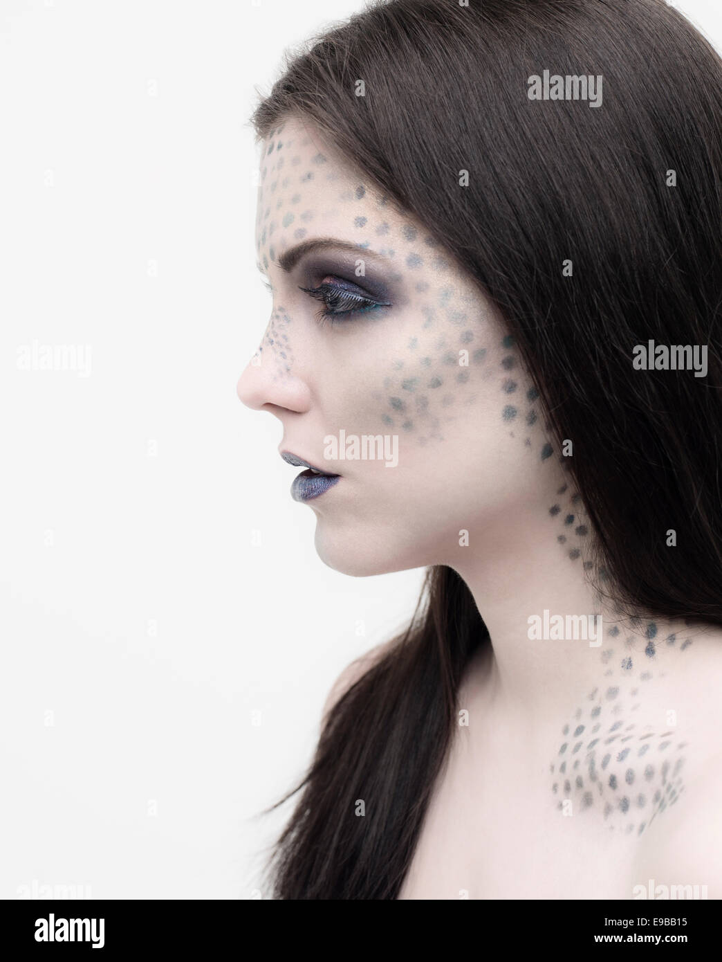 Young brunette woman with scales on her face photographed in studio in ...