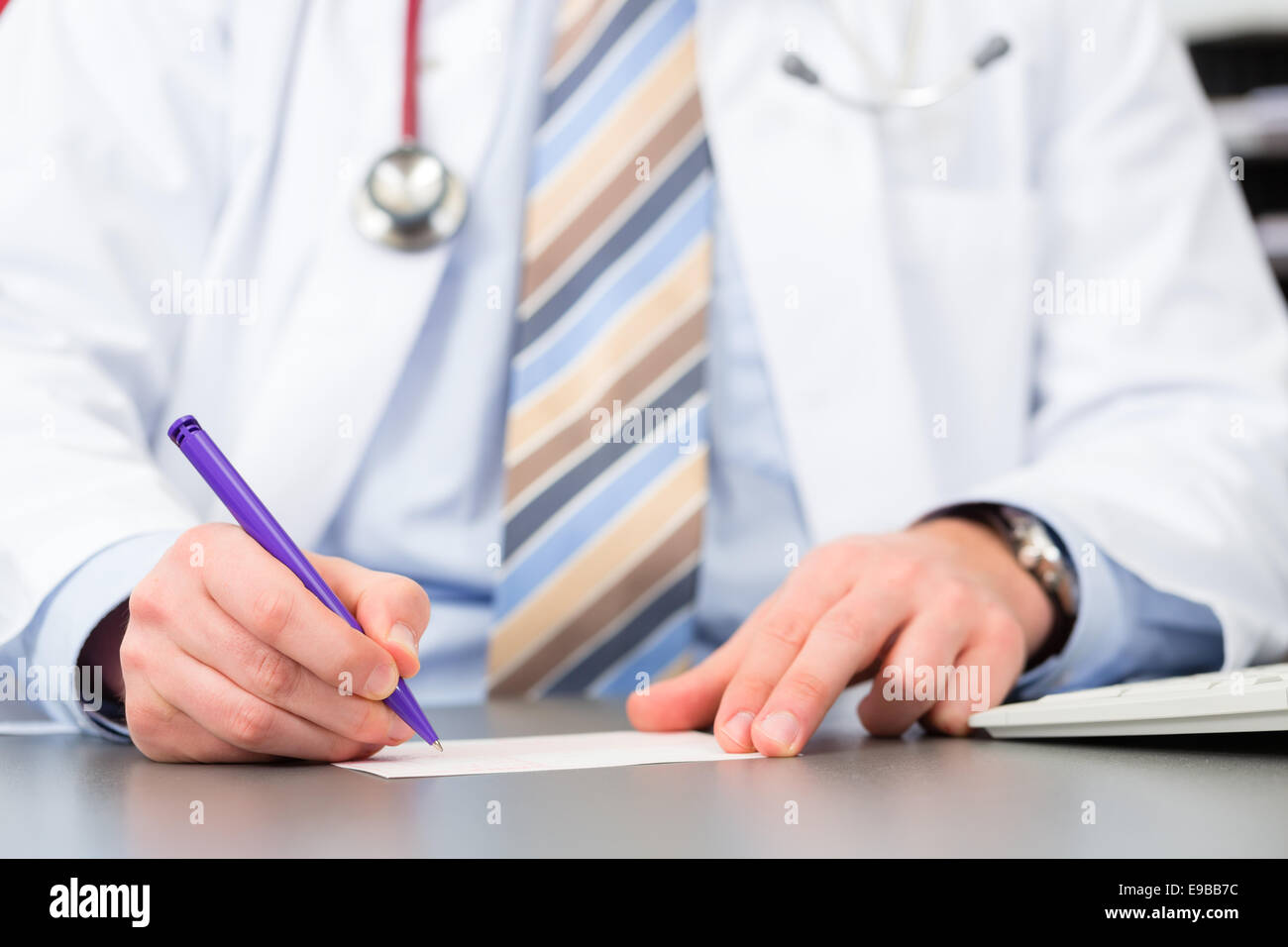 Young doctor writing medical prescription in surgery at desk Stock ...