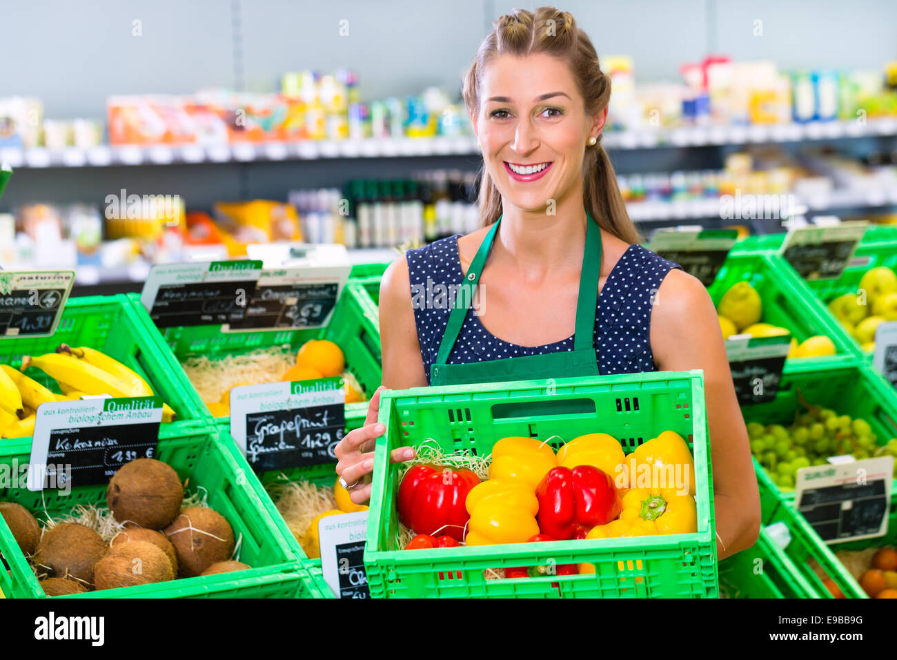 Female organic grocery shop assistant filling up coconuts storage racks ...