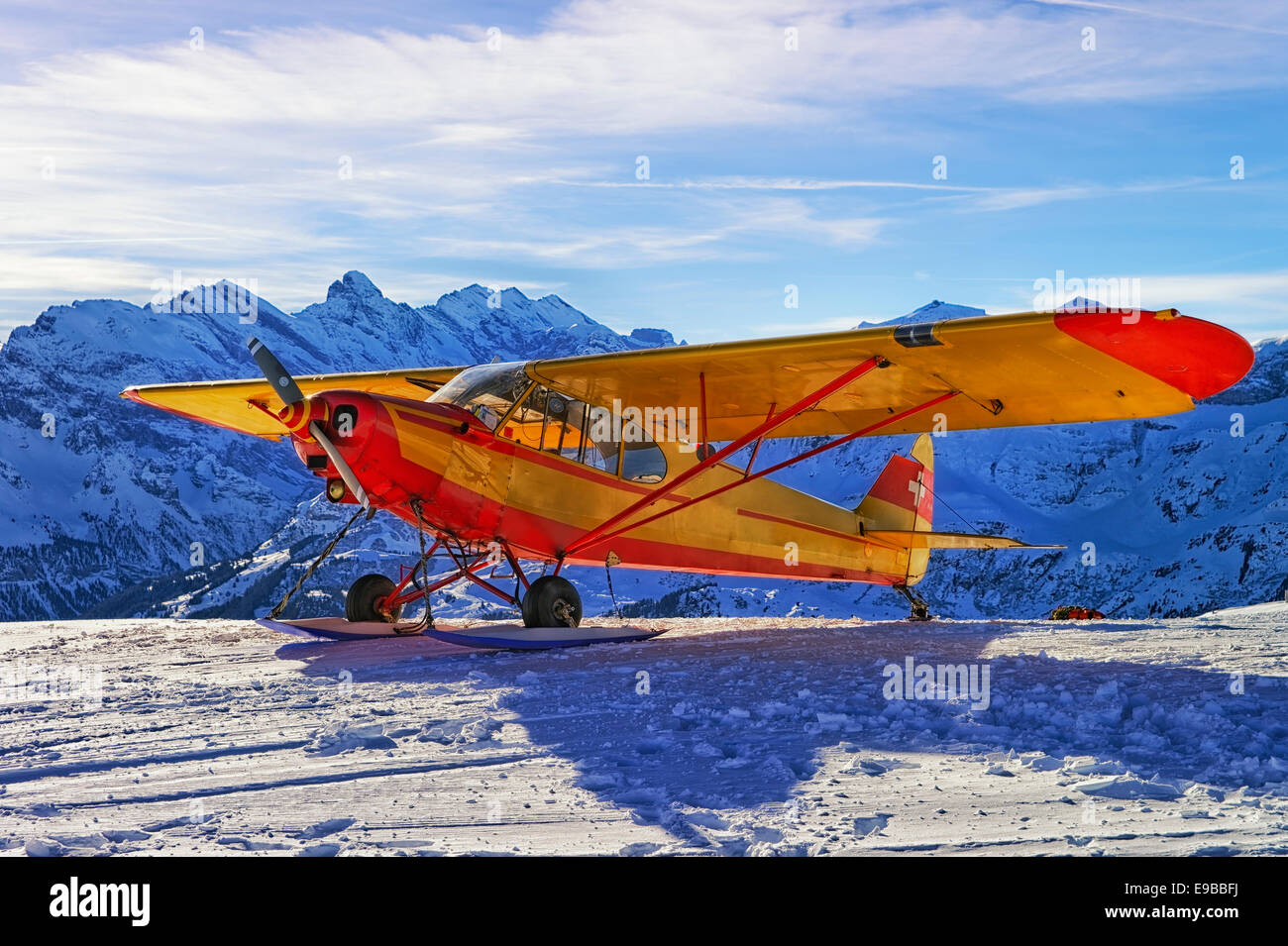 Yellow red airplane at the mountain airfield in swiss alps in front of ...