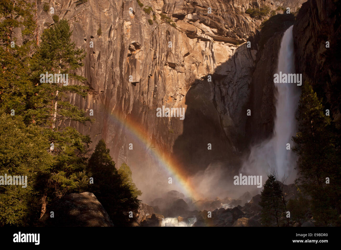 A rainbow forms at the base of Lower Yosemite Falls in Yosemite ...