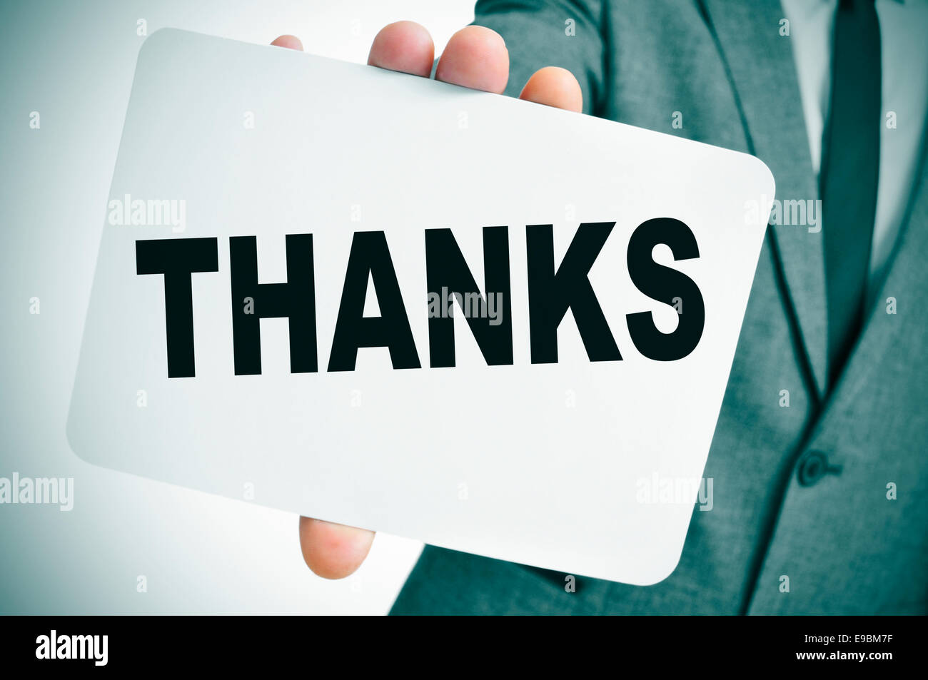 a man wearing a suit showing a signboard with the word thanks written ...