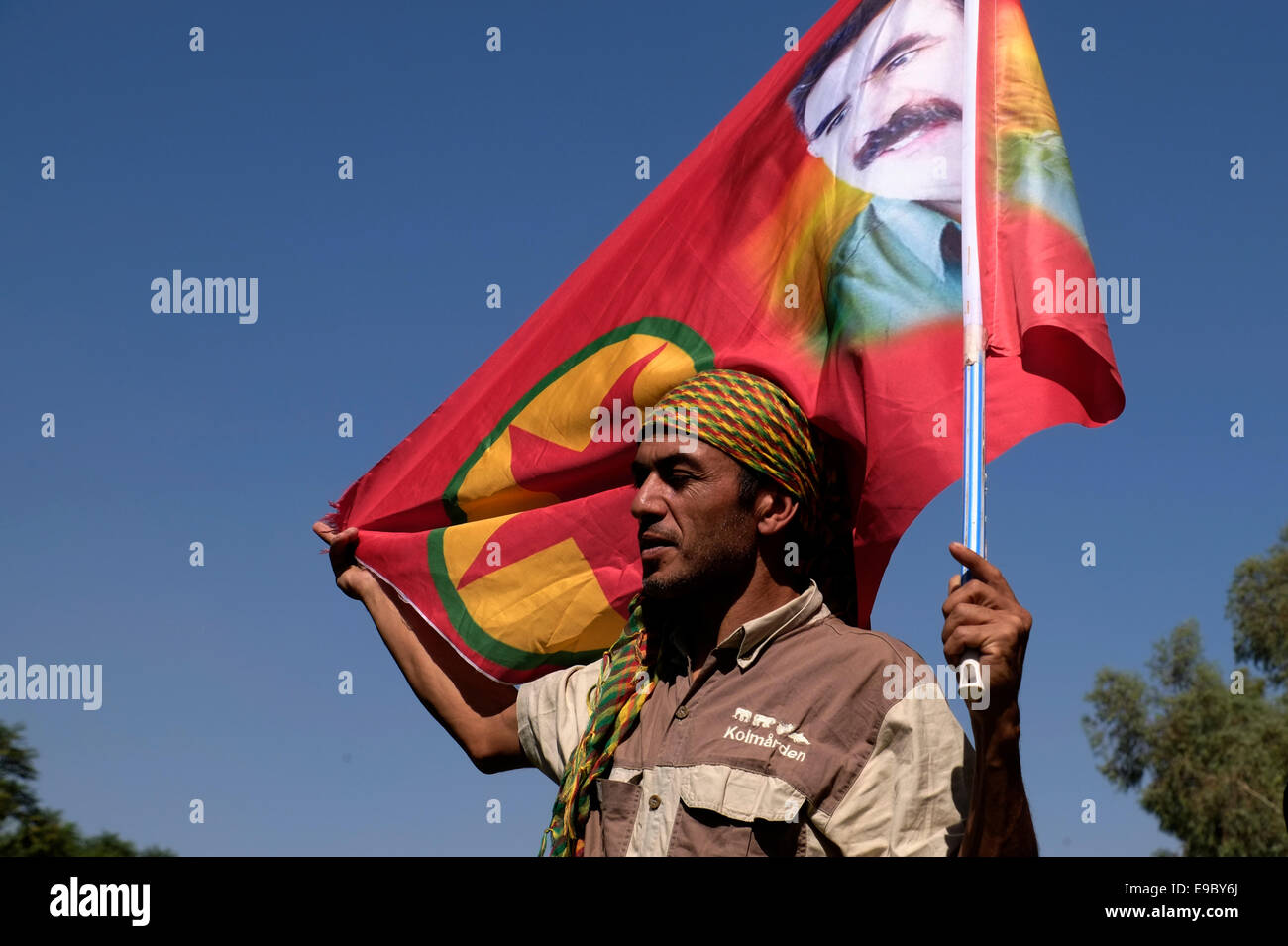 A Kurdish man holds a flag bearing the image of Abdullah Ocalan ...