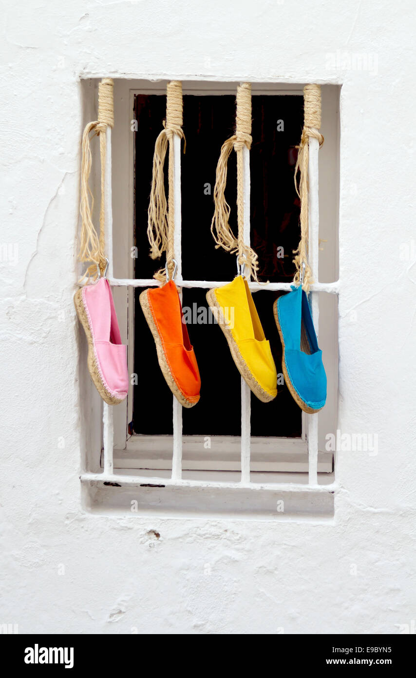 Four brightly colored shoes hanging outside a window Stock Photo - Alamy
