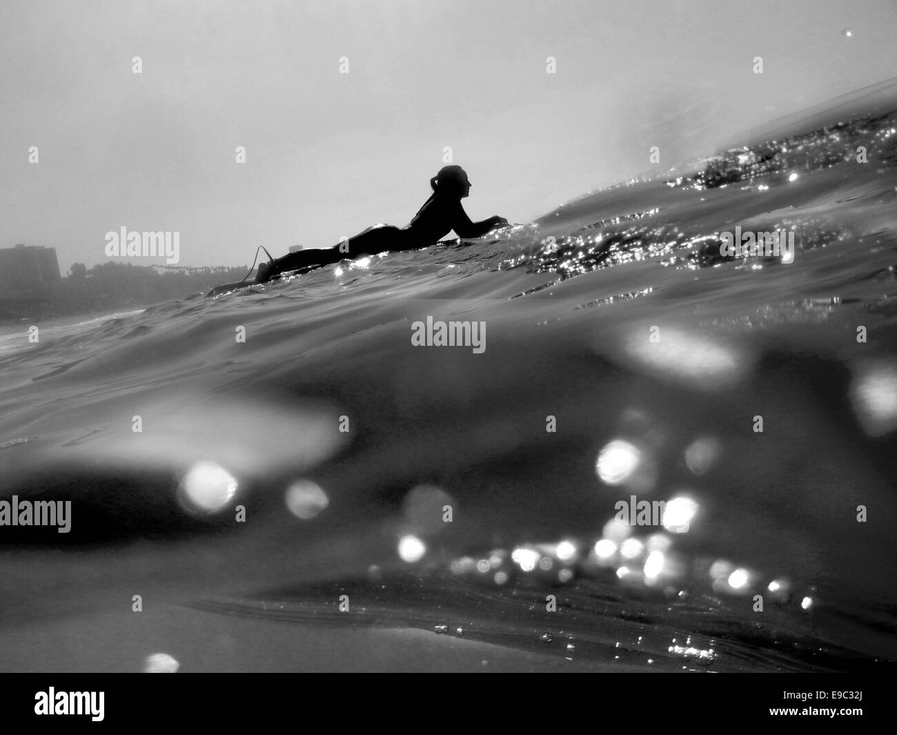 Surfer girl waiting for wave in ocean while floating over a small wave ...