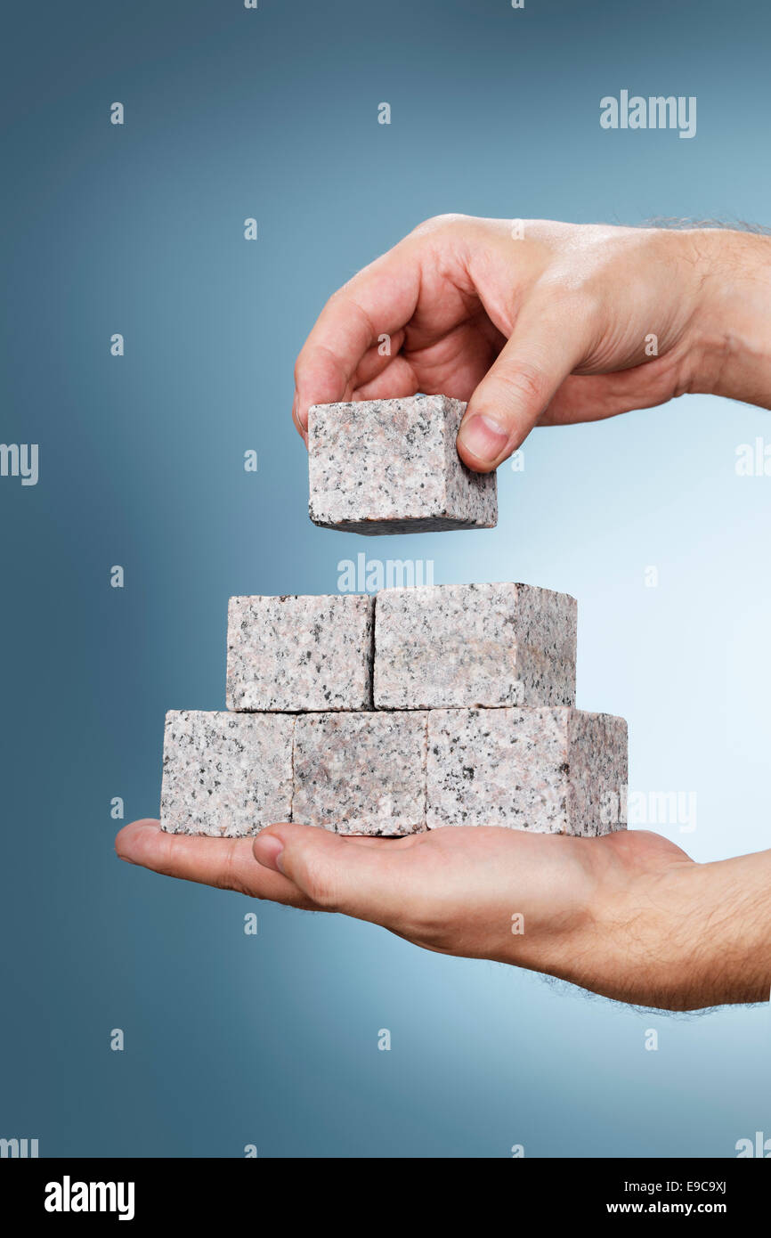Man building a pyramid of granite rock blocks in his hands Stock Photo ...
