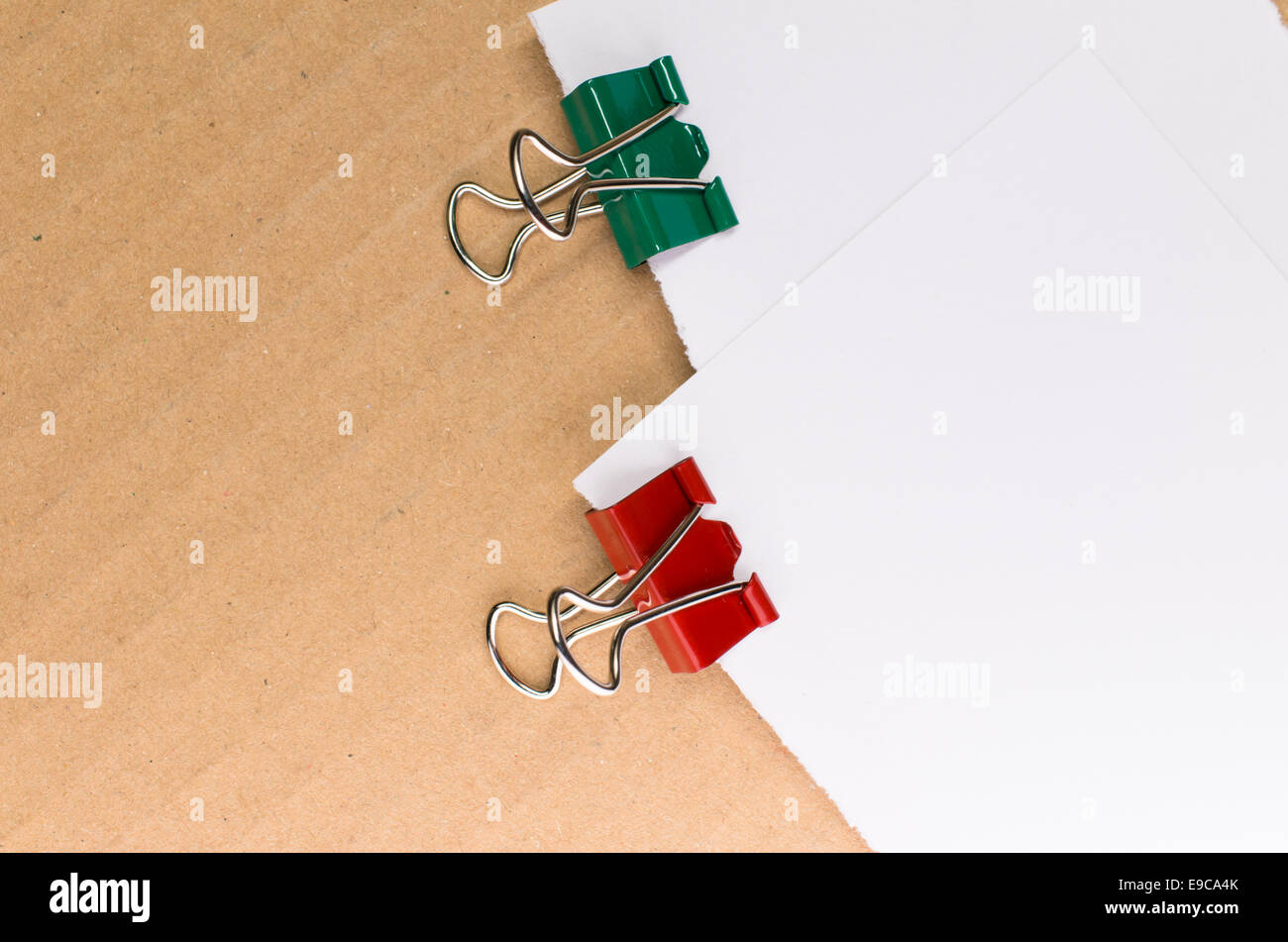 green and red metal paper clips on two white paper sheets, cardboard ...
