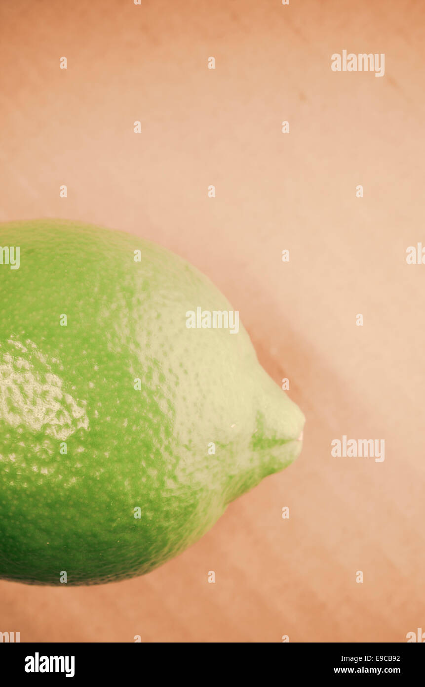 green lemon on a light brown cardboard surface Stock Photo - Alamy