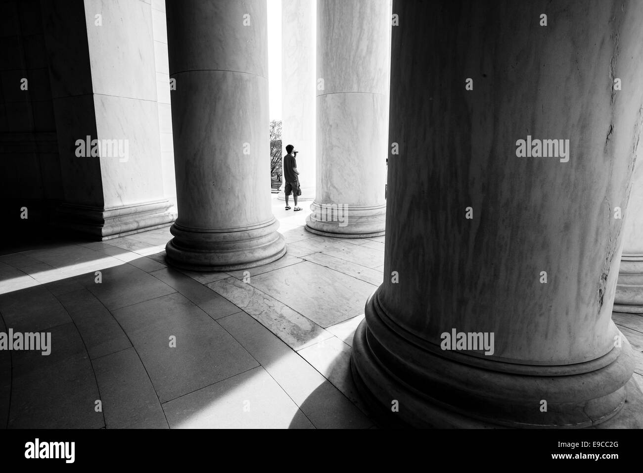 A boy stands silhouetted between the massive marble columns of the ...
