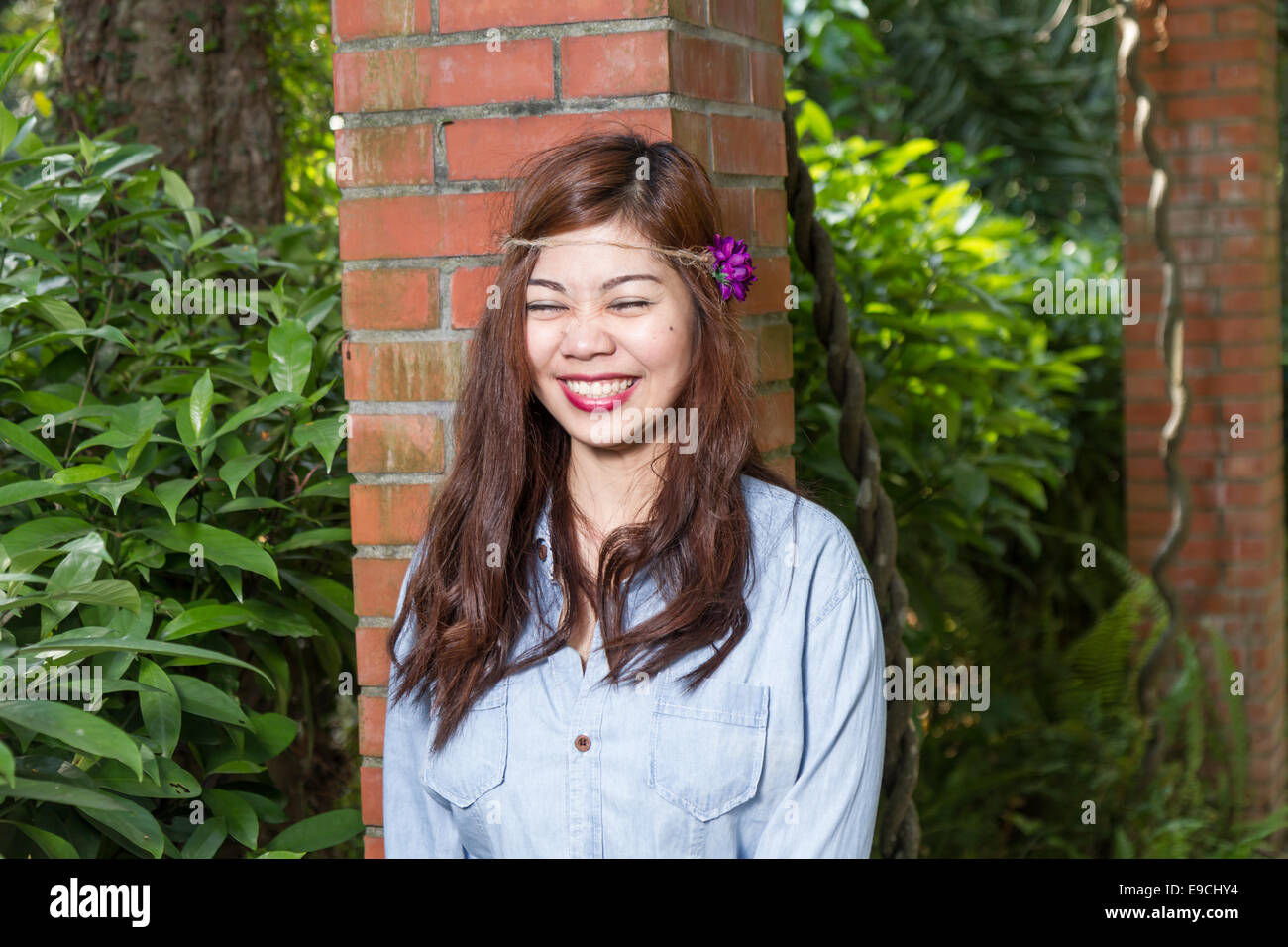 Pinoy woman in a green garden on farm, leaning against brick pillar ...