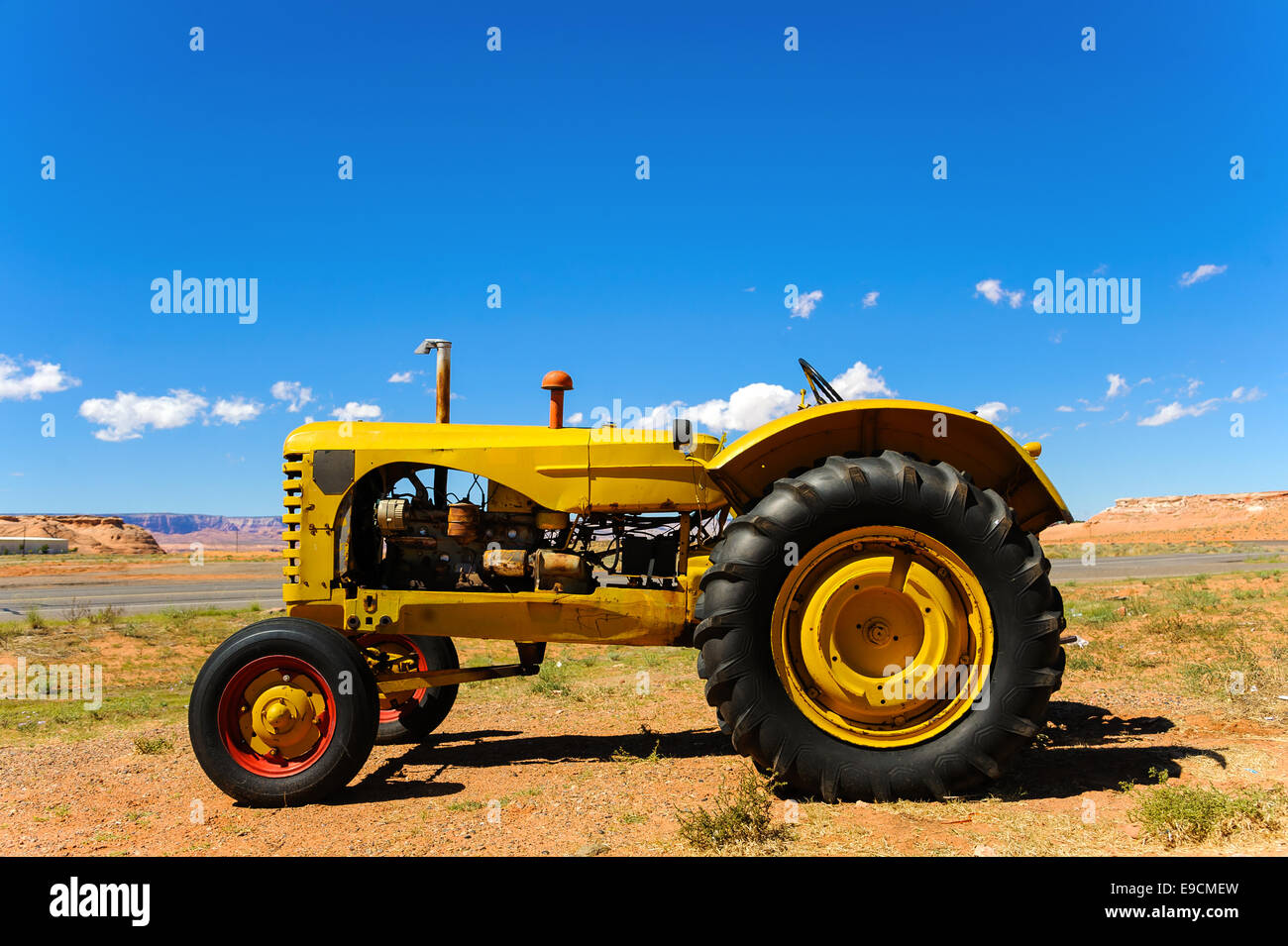 A vintage yellow tractor is seen under a bright blue sky in the desert ...