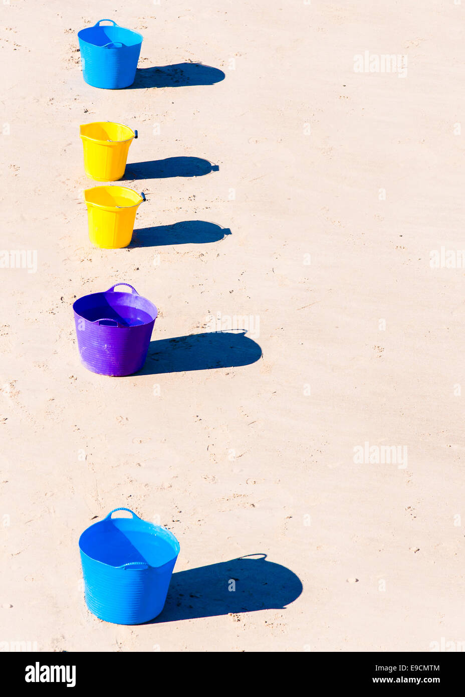 Row of colorful buckets on the beach sand Stock Photo - Alamy