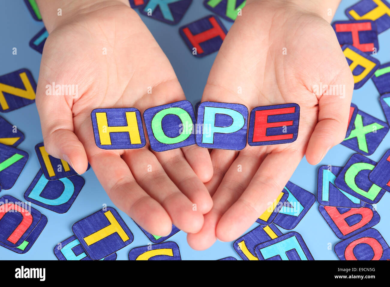 Word "Hope" in woman's hands with letters on blue background. Letters ...
